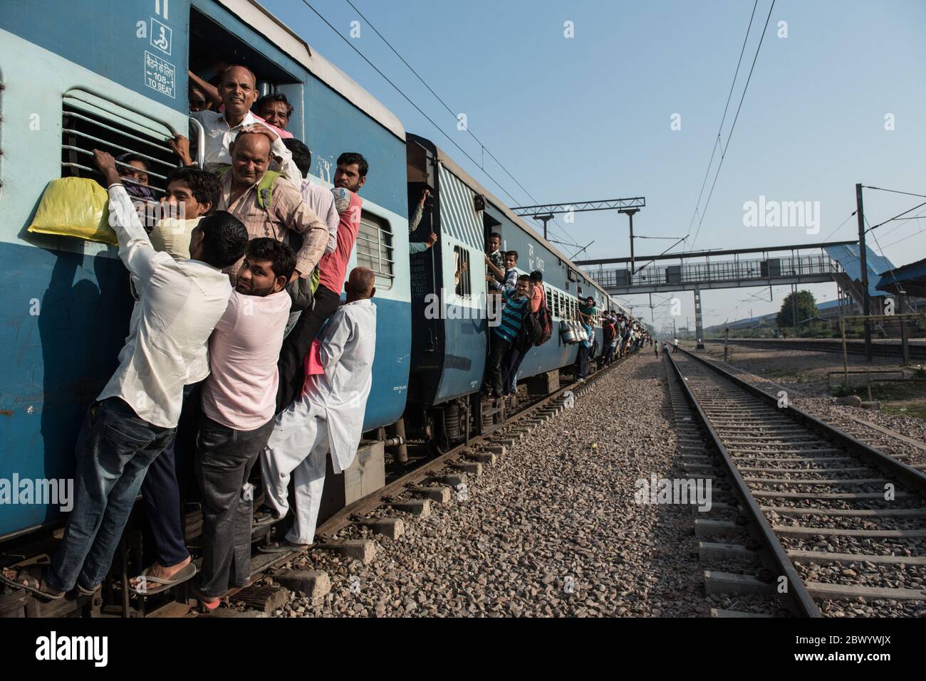 Commuters hang out of an overcrowded Indian Railways train, at Noli ...