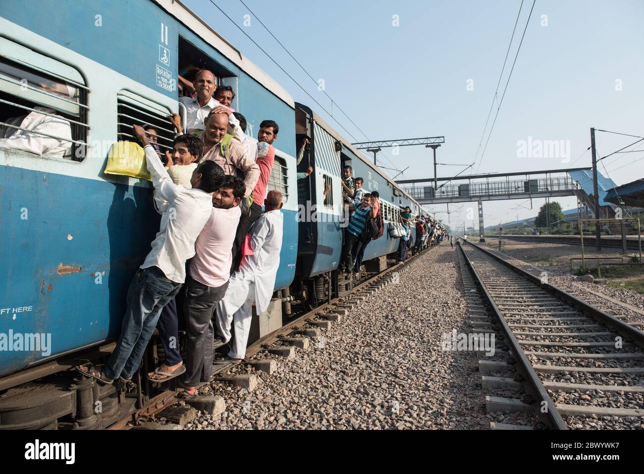 Commuters hang out of an overcrowded Indian Railways train, at Noli ...