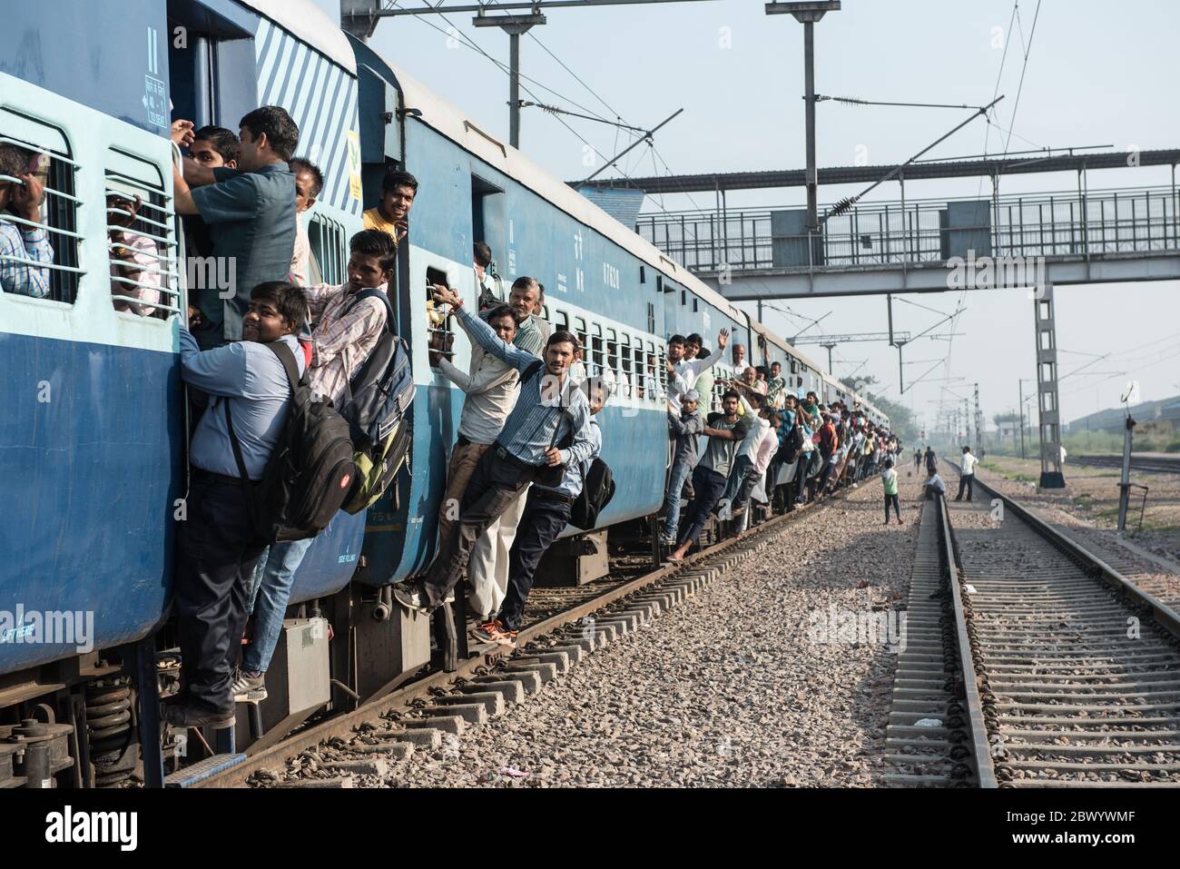 Commuters hang out of an overcrowded Indian Railways train, at Noli ...