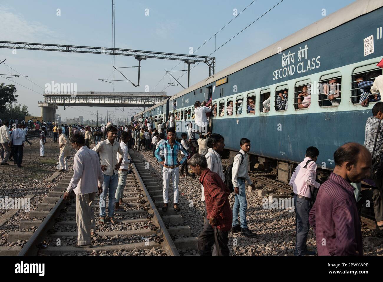 Commuters hang out of an overcrowded Indian Railways train, at Noli ...