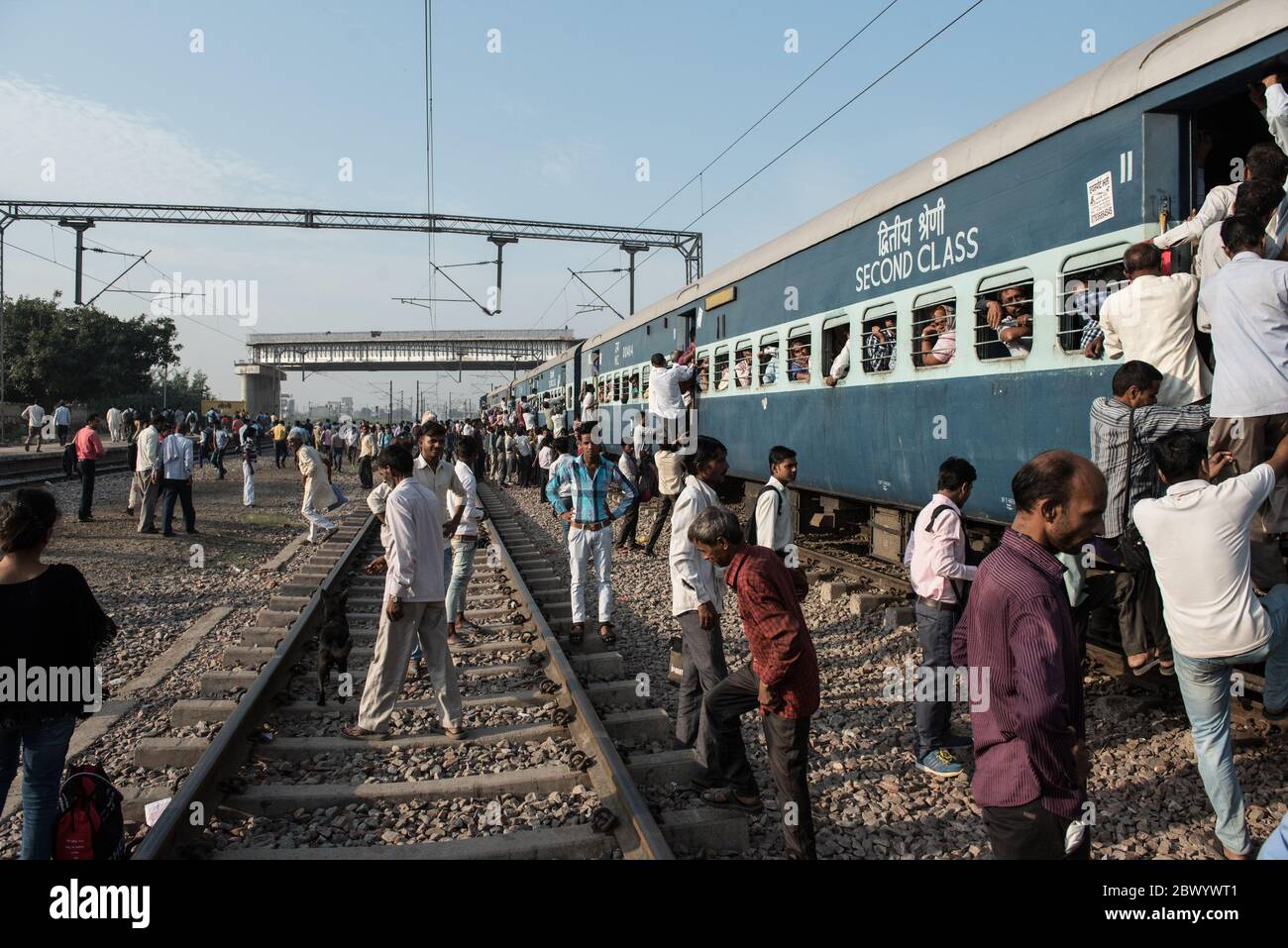 Commuters hang out of an overcrowded Indian Railways train, at Noli ...
