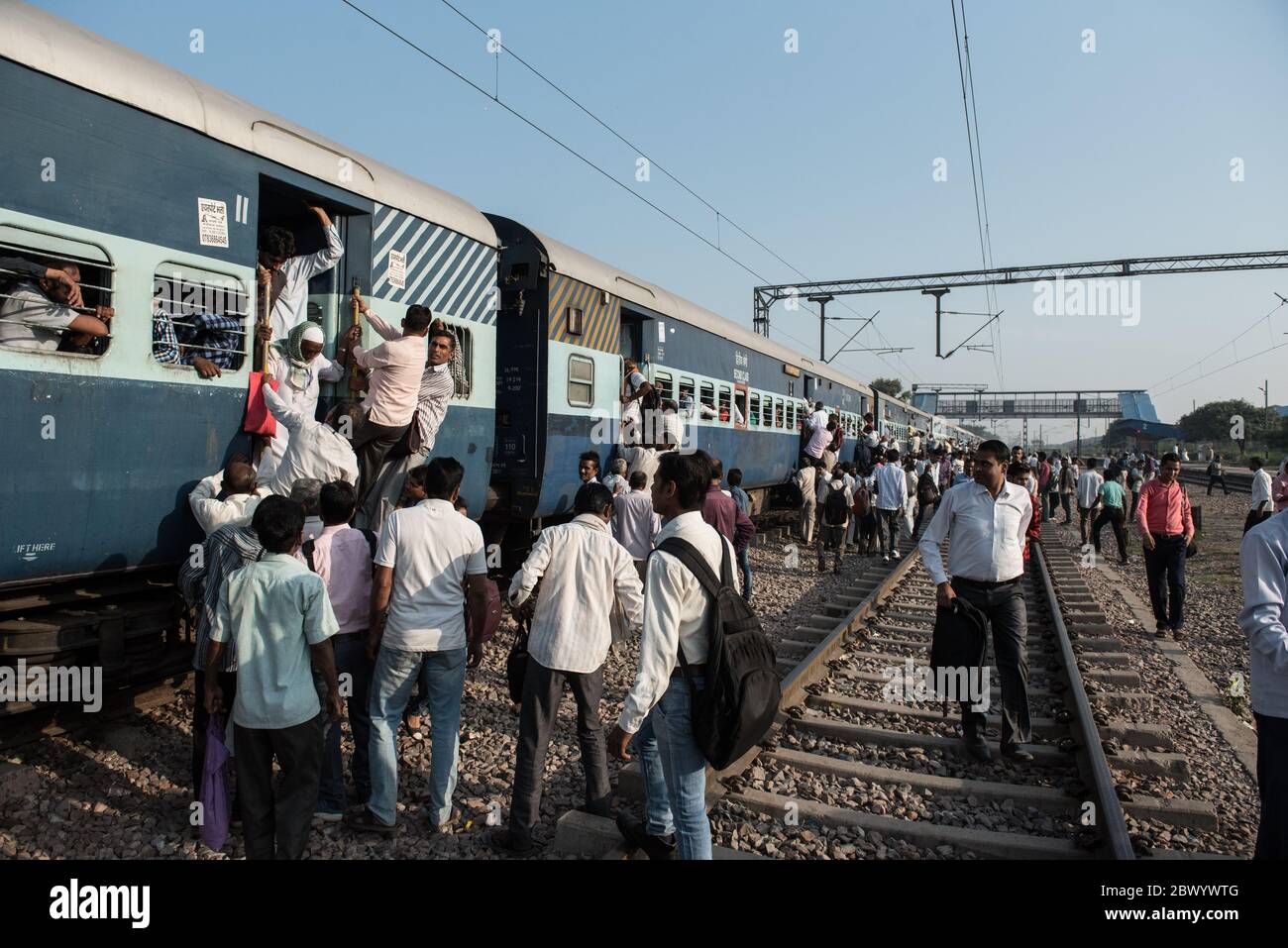 Commuters hang out of an overcrowded Indian Railways train, at Noli ...