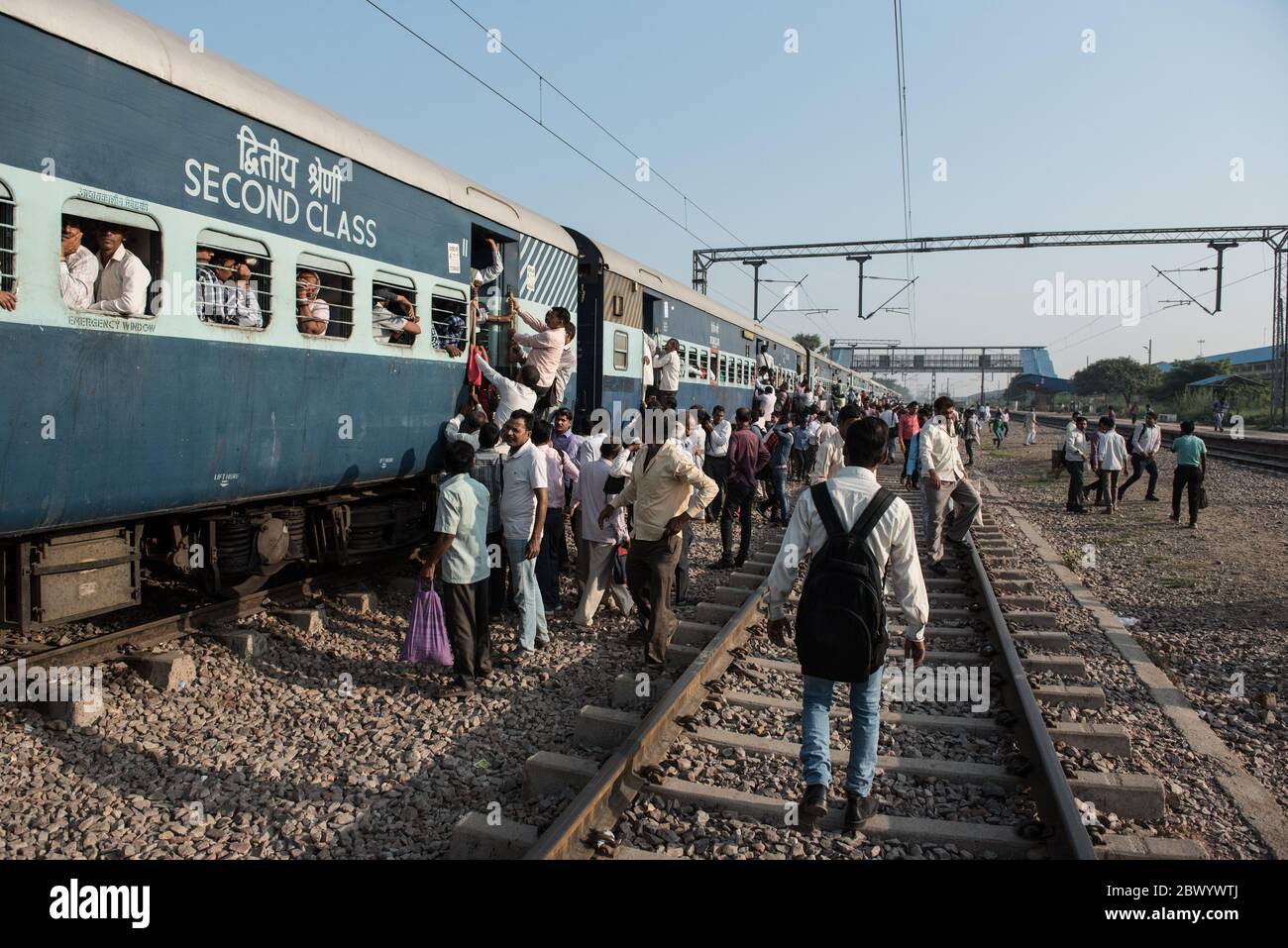 Commuters hang out of an overcrowded Indian Railways train, at Noli ...