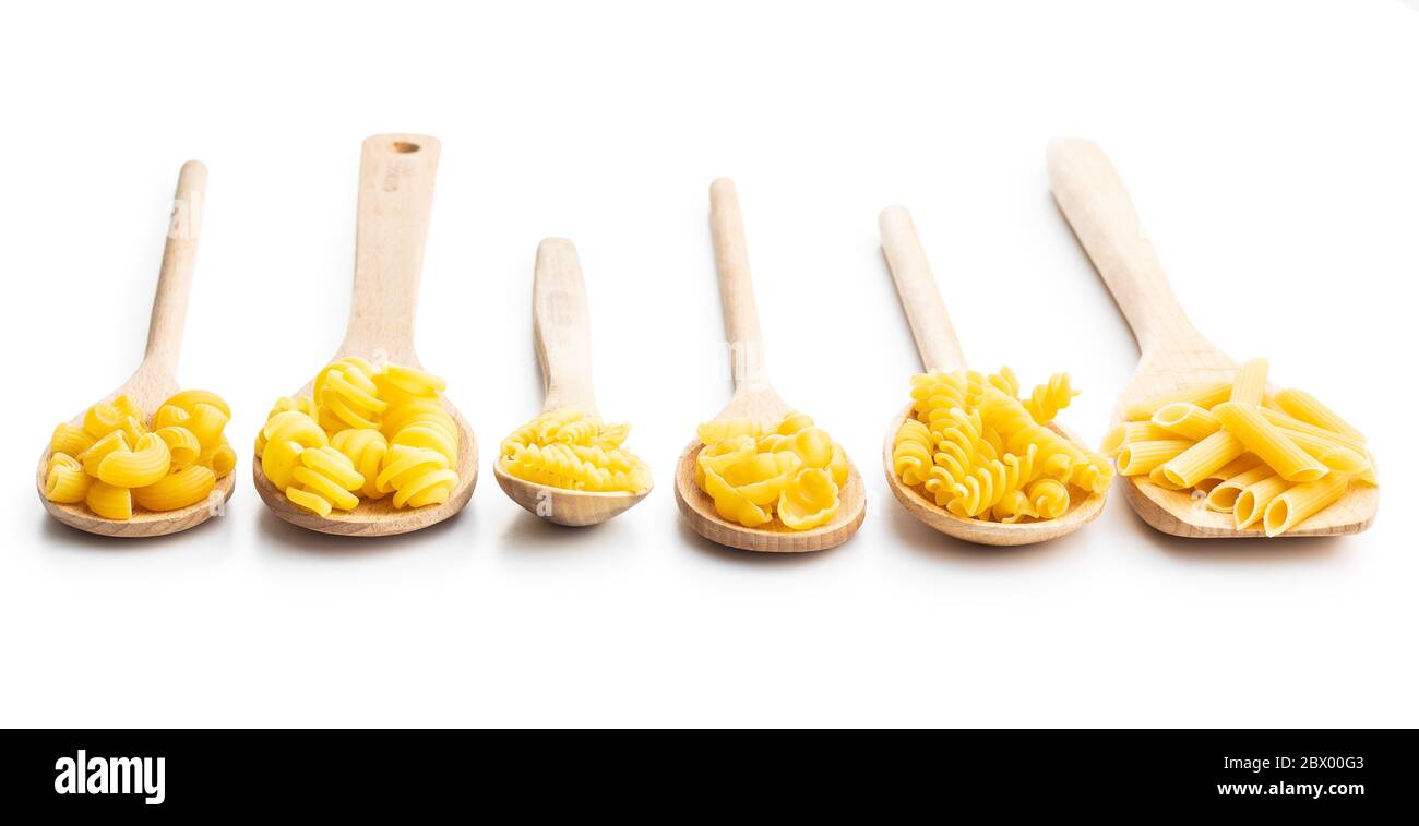 Various types of raw italian pasta in wooden spoons isolated on white ...
