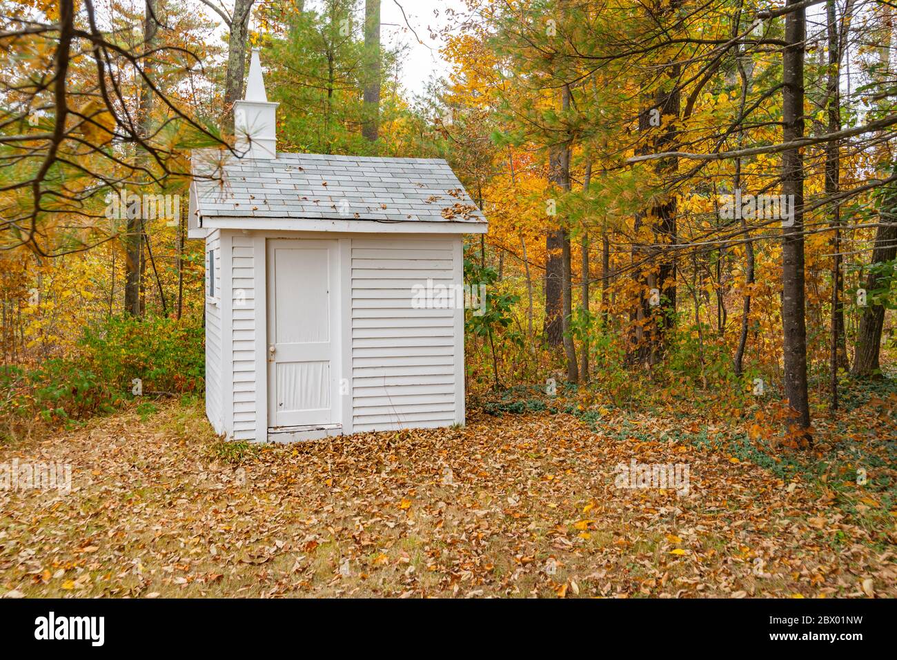 Small white wooden building standing among trees in autumn colors and ...