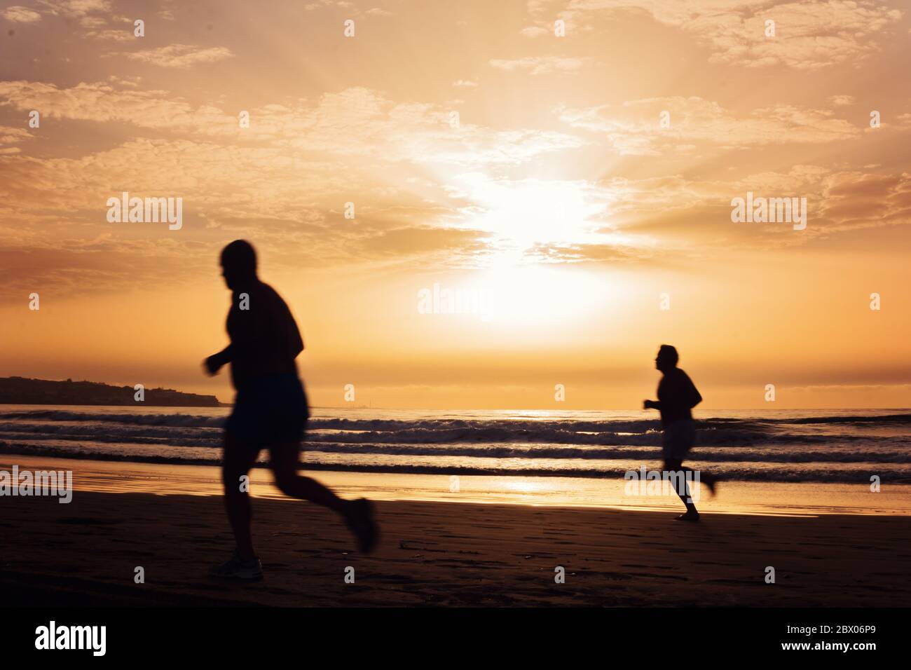 sport and healthy lifestyle, two people jogging at sunset on the beach ...