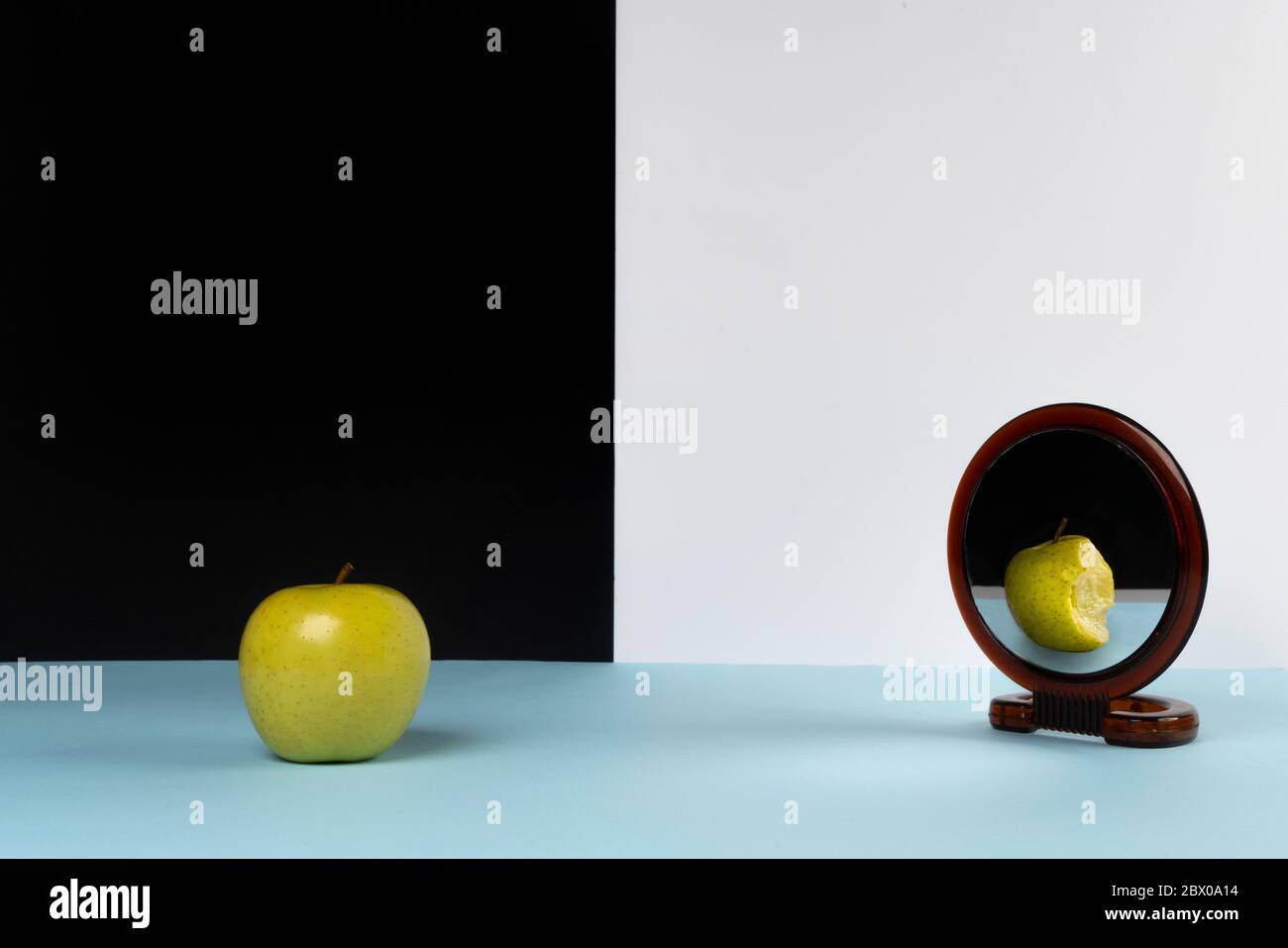 the apple in front of the mirror that appears bitten Stock Photo - Alamy