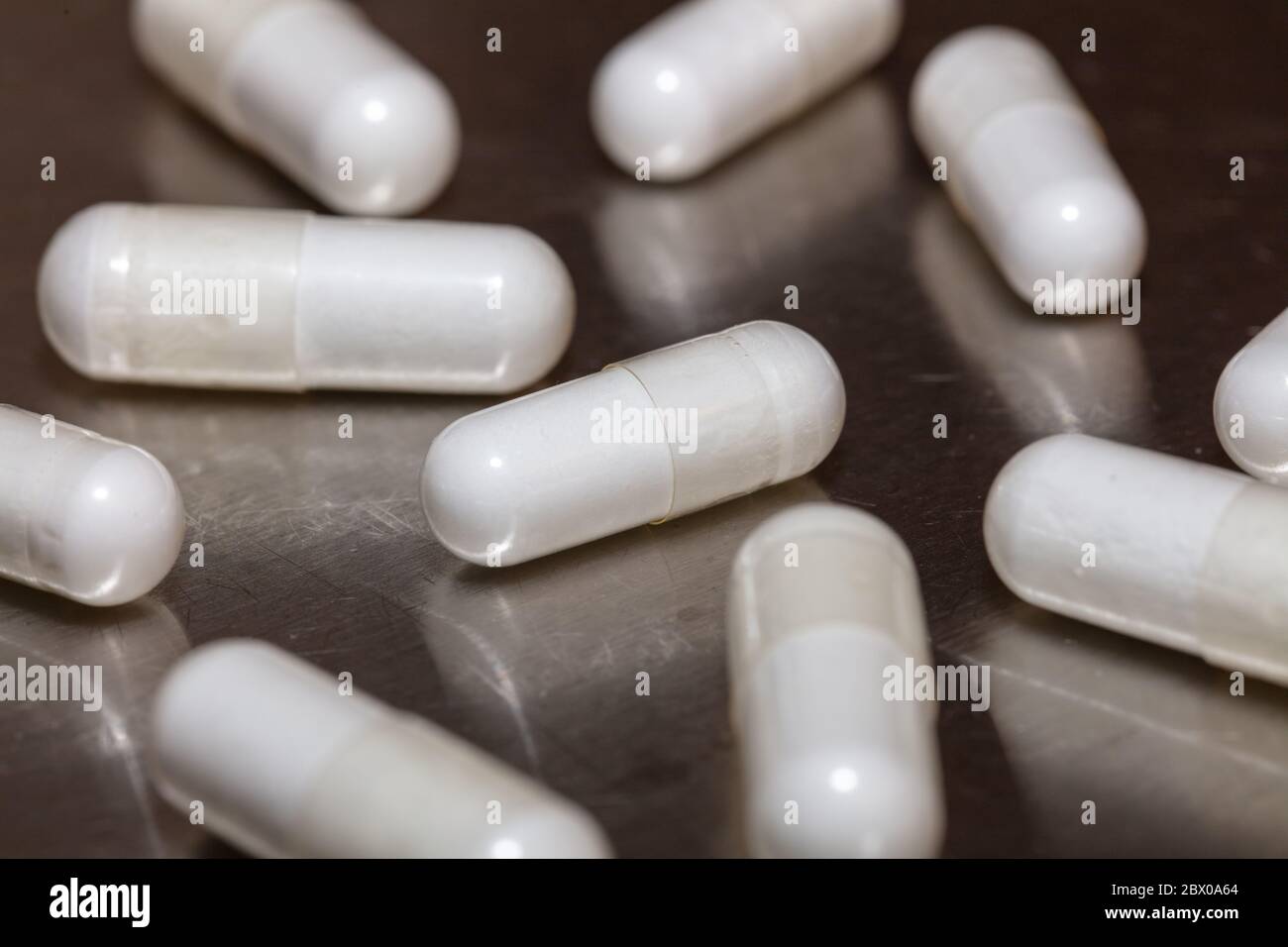White pills scattered on scratched metal surface. Majority of the pills ...