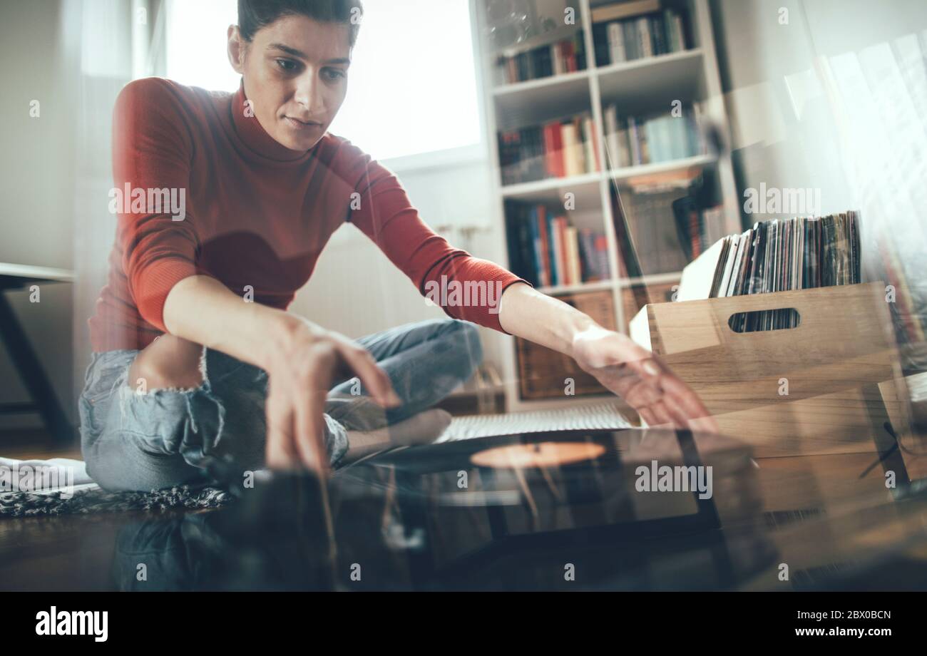 Woman sitting on floor playing vinyl record on turntable Stock Photo ...