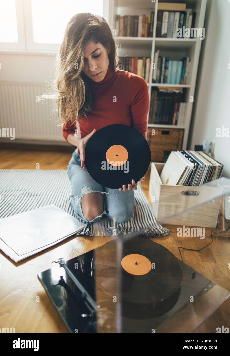 Young woman sitting on floor with vinyl record. Playing music on ...