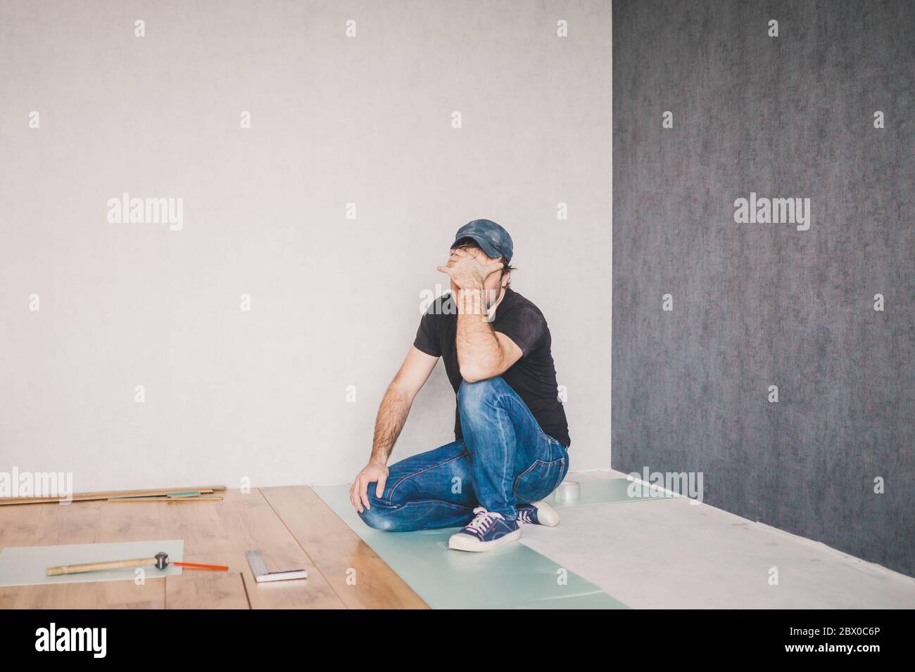 Tired flooring technician holds his hand on his head - hard work Stock ...
