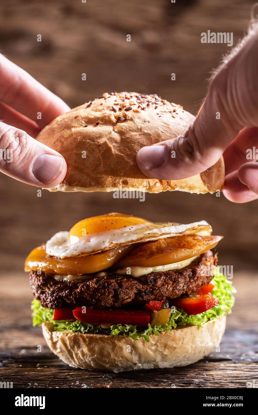 Two hands put the top bun part on freshly made beef burger Stock Photo ...