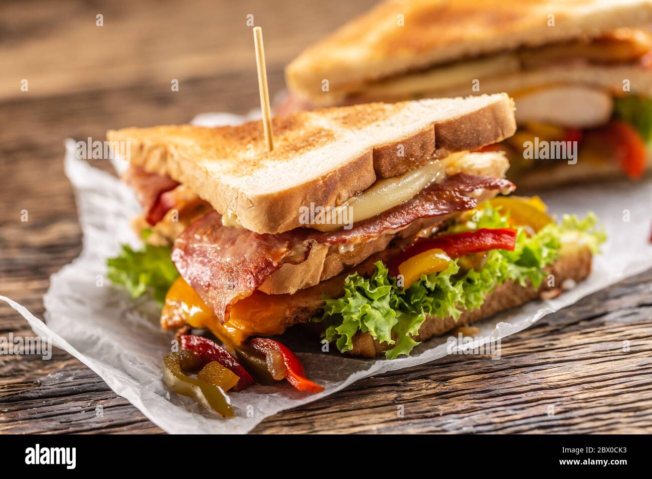 Club sandwich on a rustic table witch chicken, bacon, pepper and ...