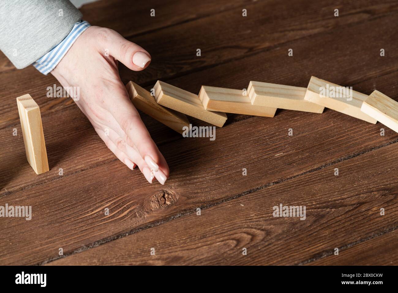 Business woman interrupting domino effect Stock Photo - Alamy
