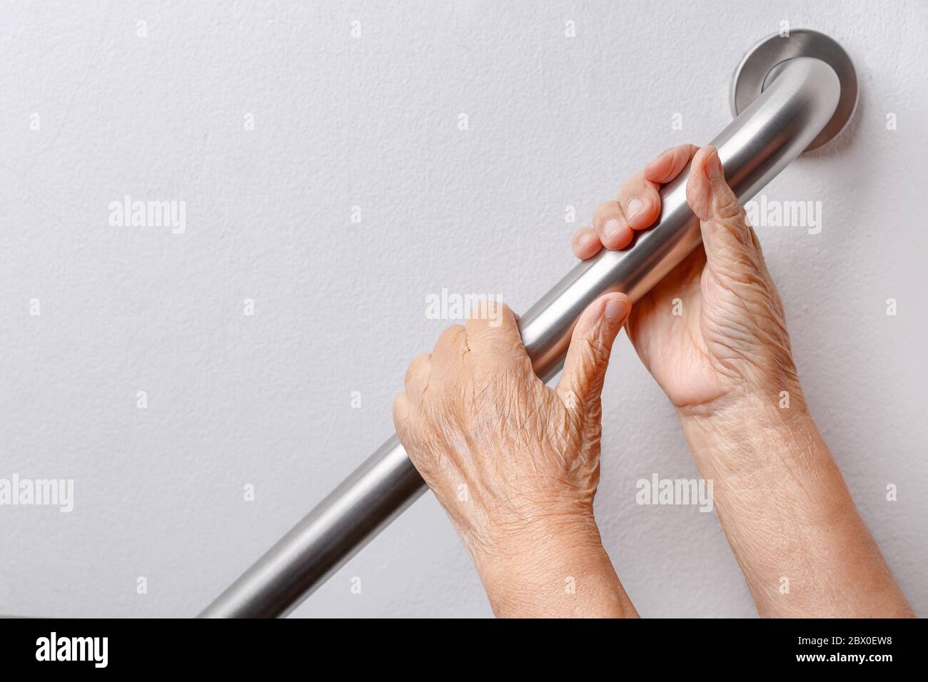 Elderly woman holding on handrail for safety walk steps Stock Photo - Alamy