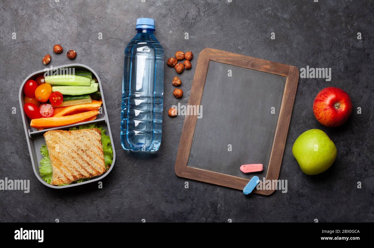 Healthy lunch box with sandwich and vegetables on stone table. Top view ...