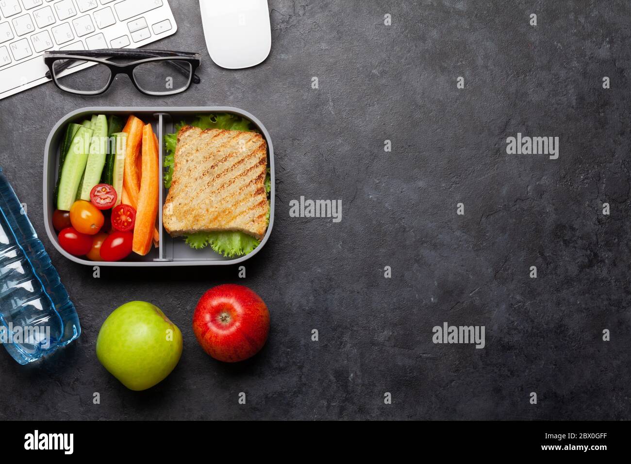 Healthy lunch box with sandwich and vegetables on office table. Top ...