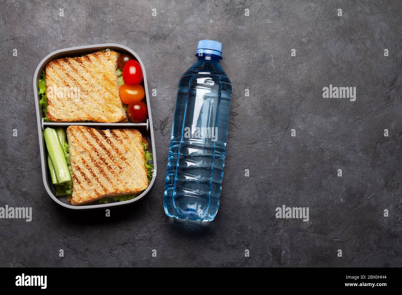 Healthy lunch box with sandwich and vegetables on stone table. Top view ...