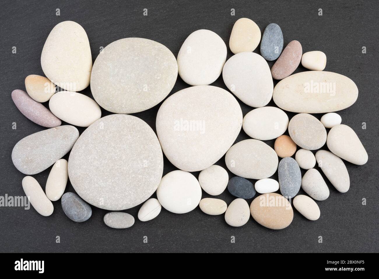Top view of arranged pebble stones on black slate background Stock ...