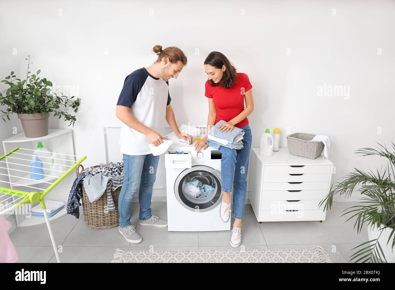 Happy young couple doing laundry at home Stock Photo - Alamy