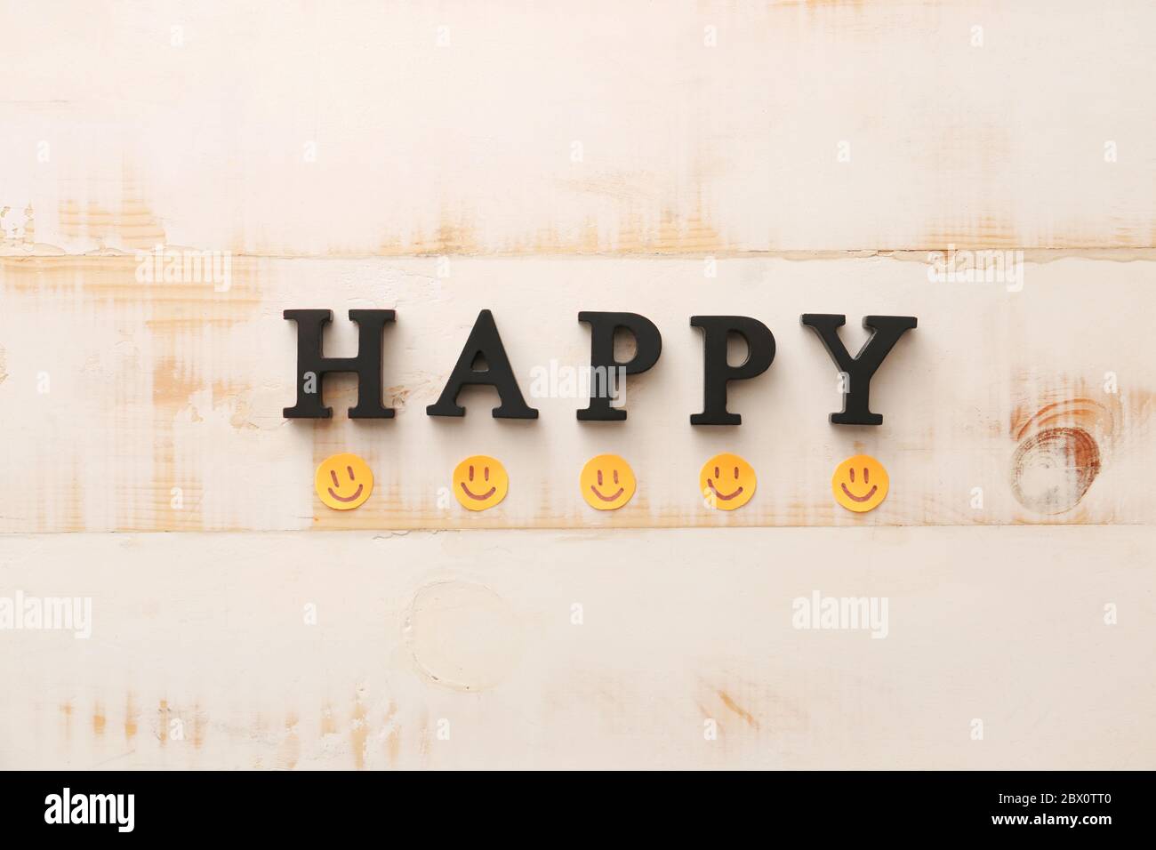 Word HAPPY and paper smiles on white wooden background Stock Photo - Alamy