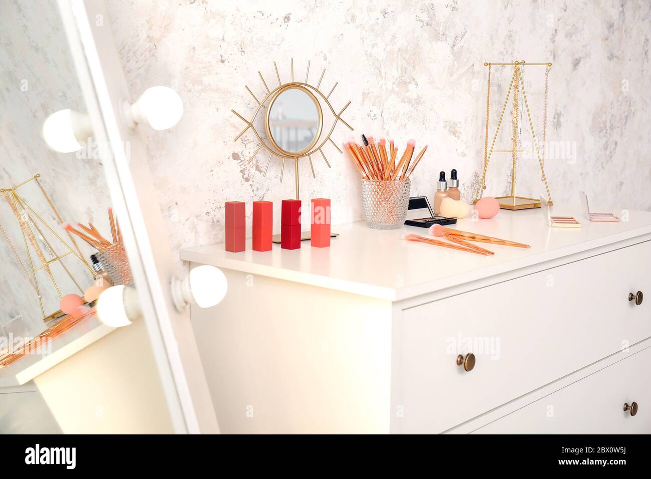 Mirror and makeup cosmetics on chest of drawers in modern dressing room ...