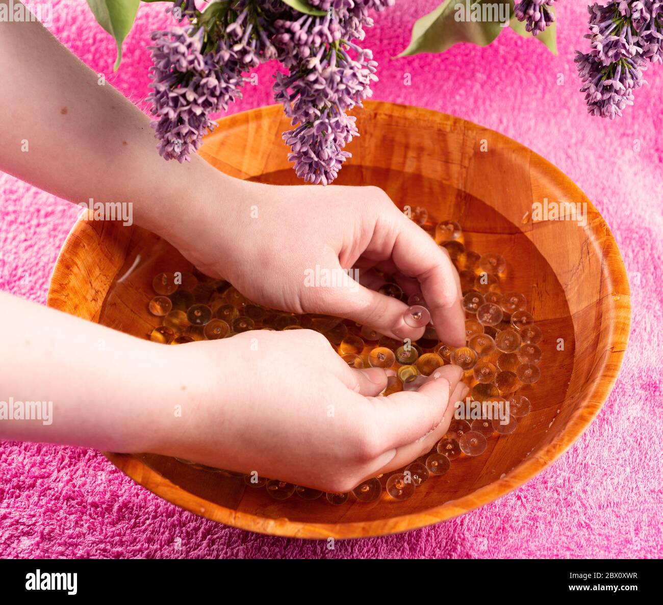 SPA treatment for fingers in a bowl with glass balls and lilac petals ...