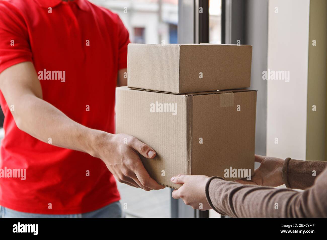 Receiving parcel at home. Courier gives cardboard boxes to customer ...