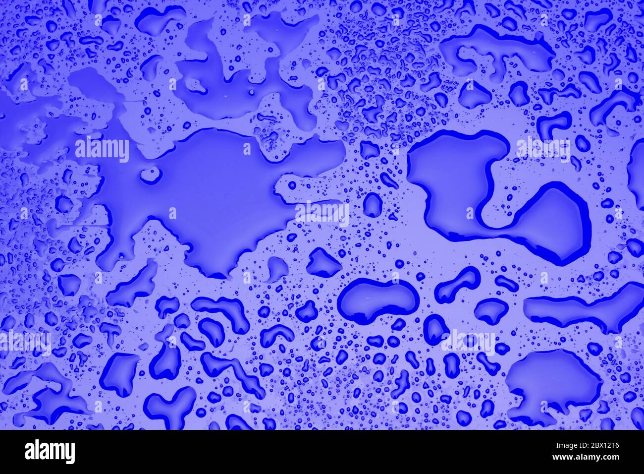 Transparent drops of water on a smooth and shiny colored surface. Water ...