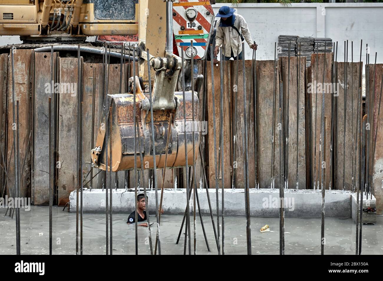Construction worker immersed in water working with a backhoe operator ...