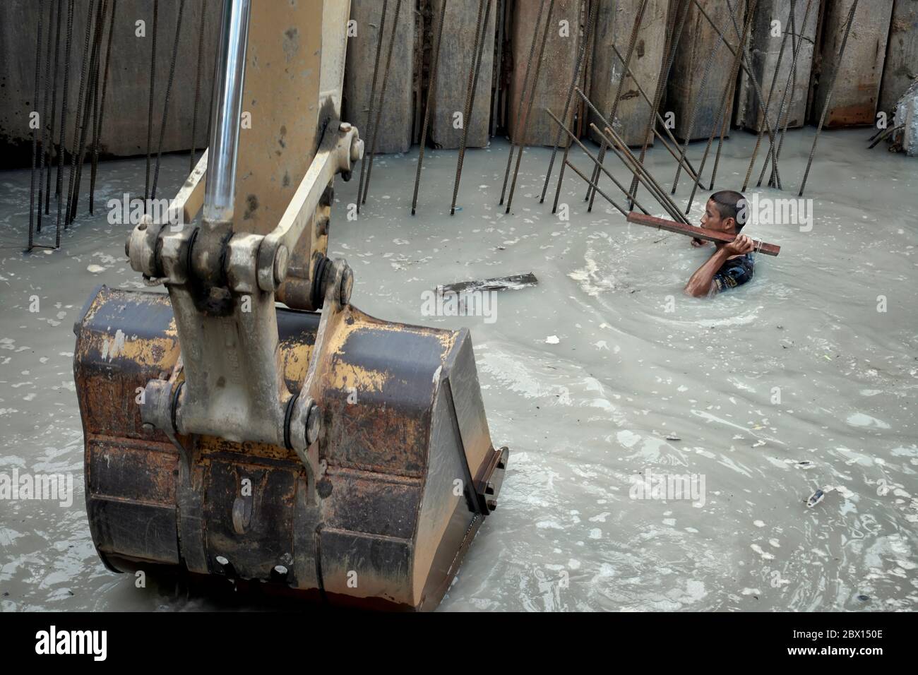 Construction worker immersed in water working with a backhoe operator ...