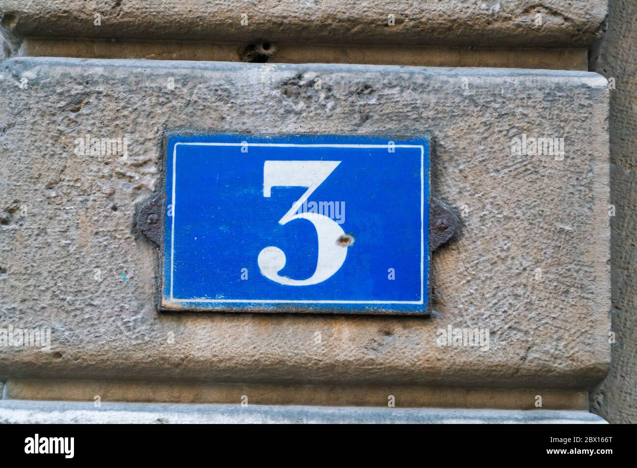 House number 3 White on blue on an old metal limestone wall of a ...