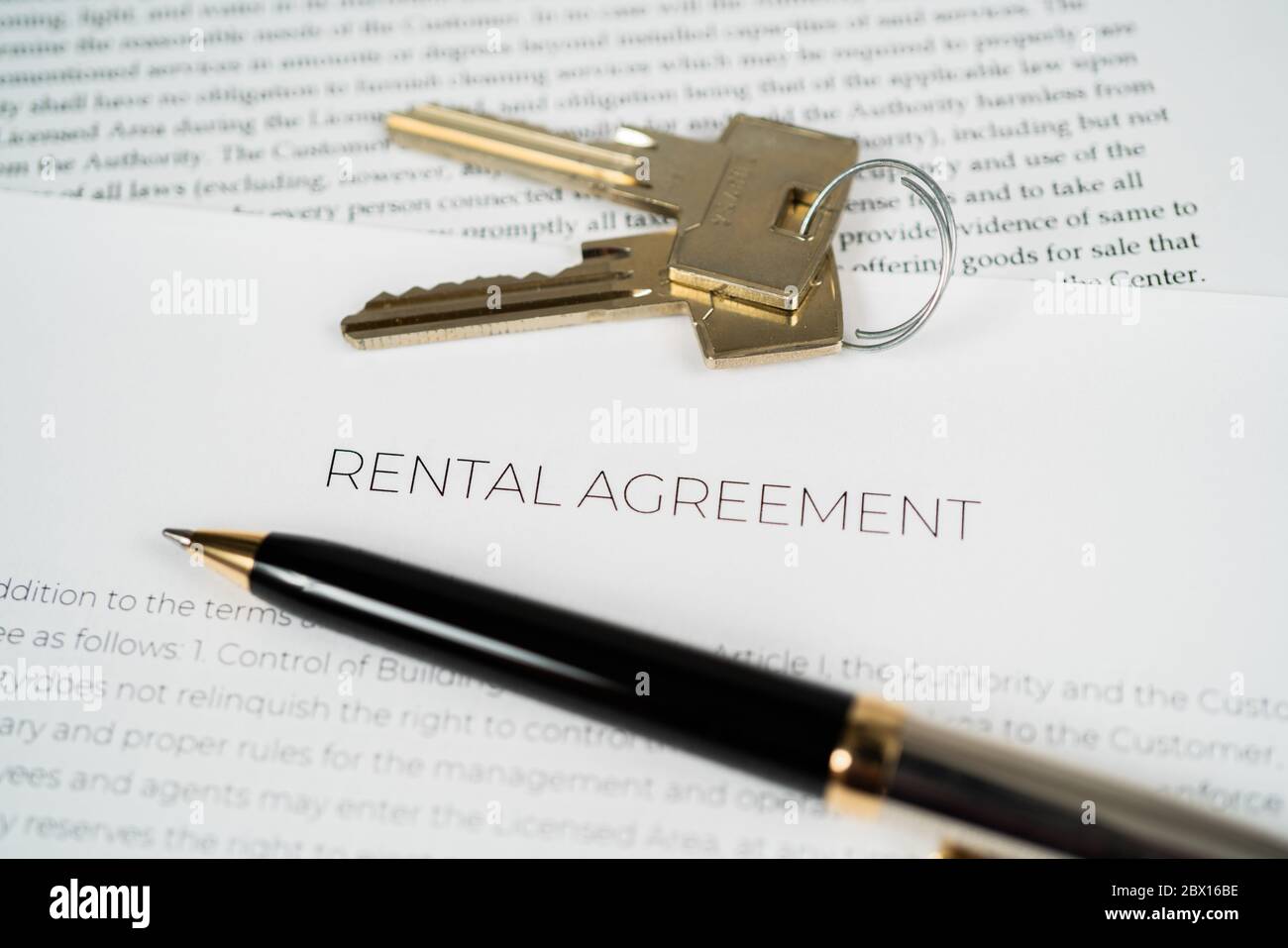 House keys and pen on top of a Rental agreement ready to be signed ...