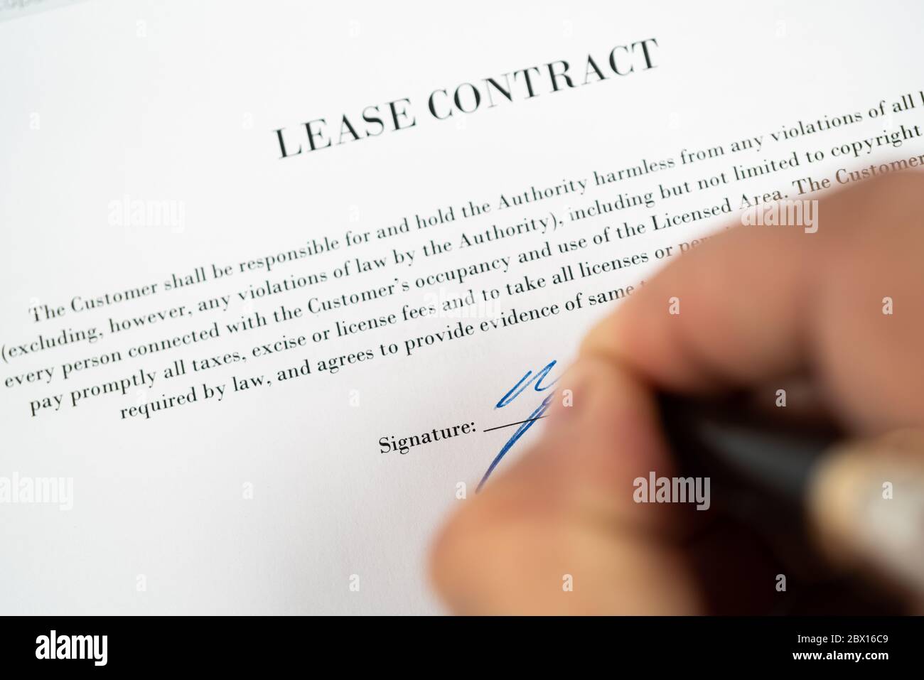 Close up hand with pen on the signature line on a lease contract ready ...