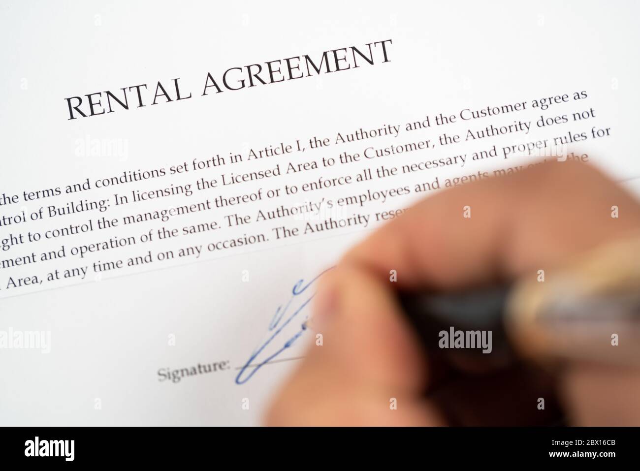 Close up hand with pen on the signature line on a rental agreement ...