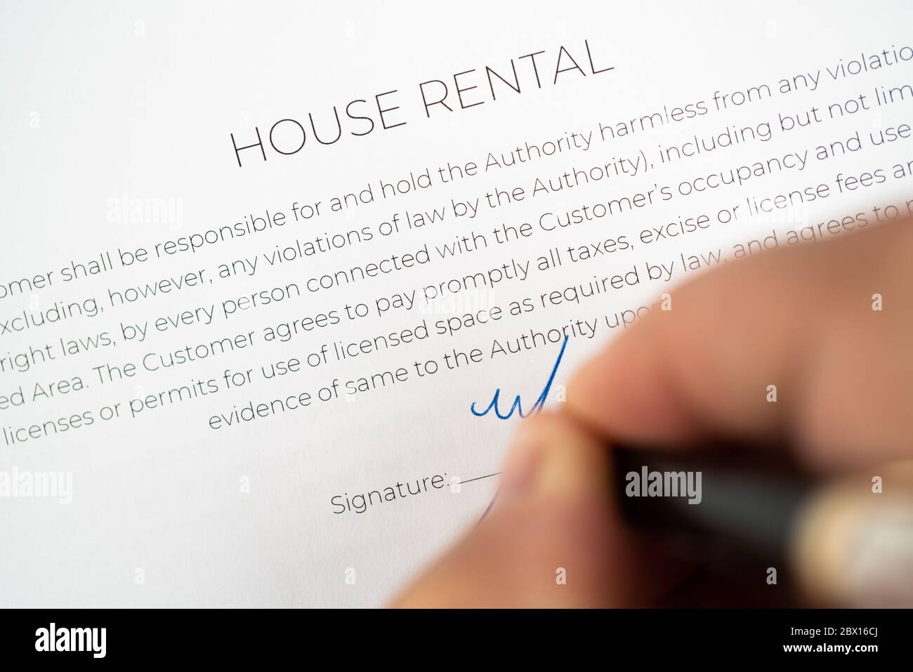 Close up hand with pen on the signature line on a house rental ...