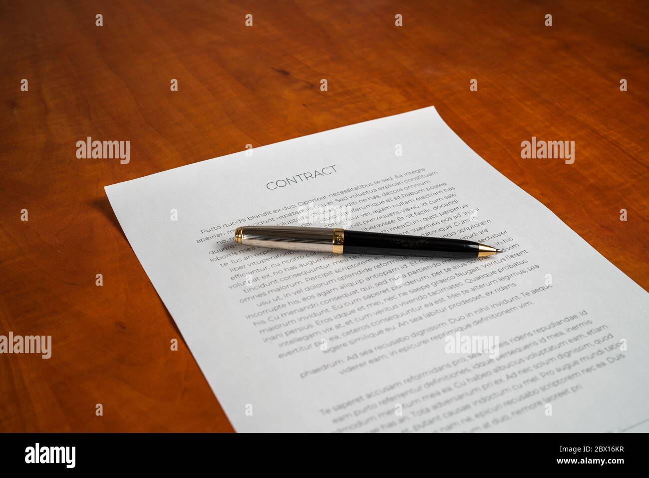 Contract with a pen ready to be signed on a wooden desk Stock Photo - Alamy