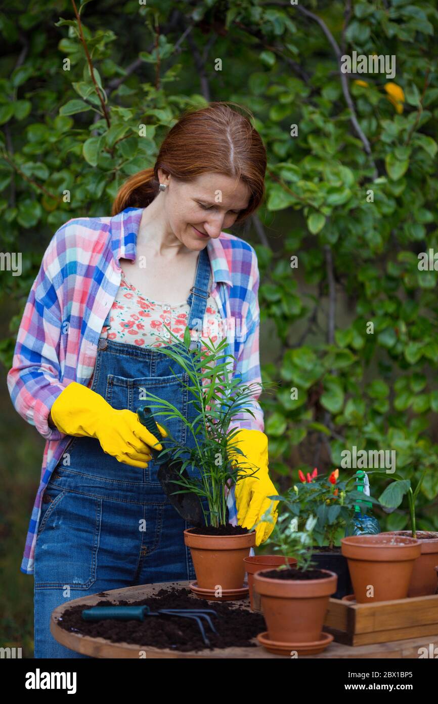 girl planting flowers in the garden. flower pots and plants for ...