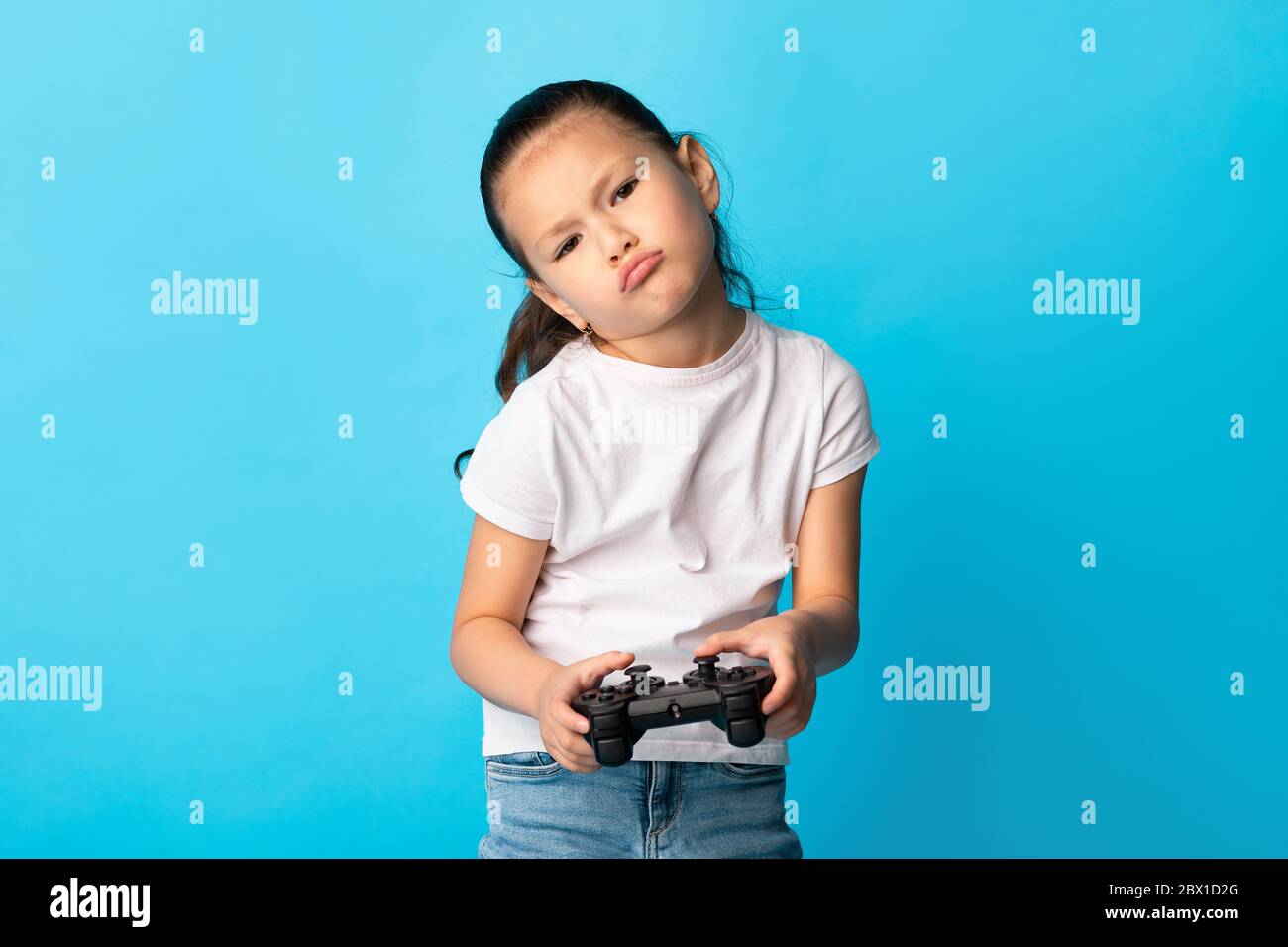 Unhappy asian kid playing video game using joystick Stock Photo - Alamy