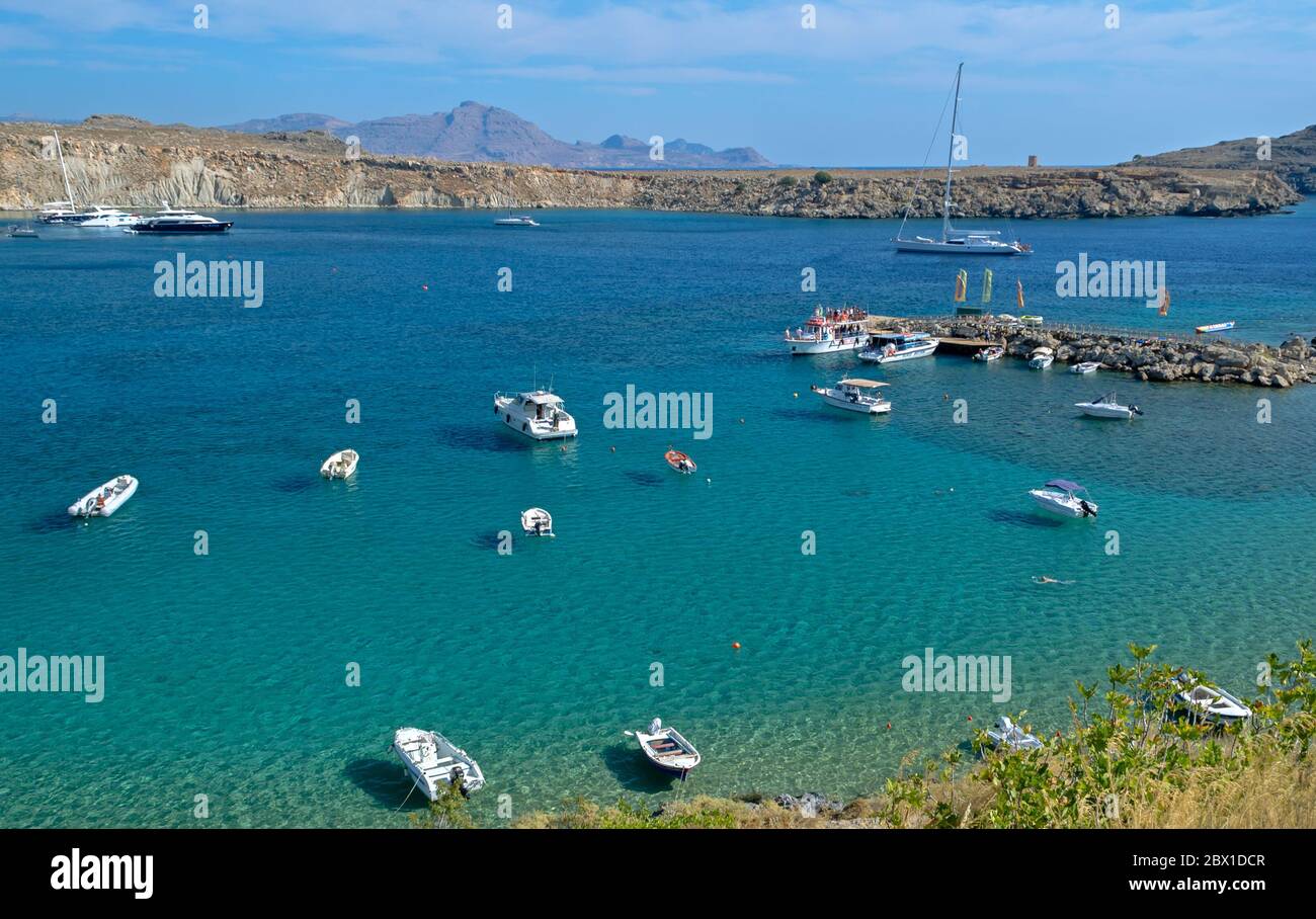 Lindos Bay, Rhodes with boats floating on the crystal clear water Stock ...