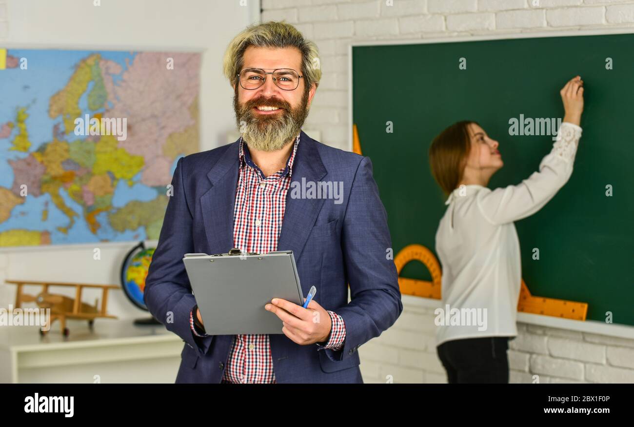 Teaching materials. Who is absent today. Small girl at chalkboard. Back ...