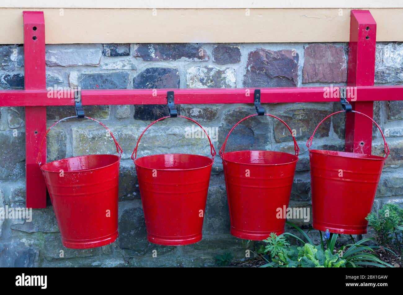 Four red buckets hanging on a wall. Backgound maybe Stock Photo - Alamy
