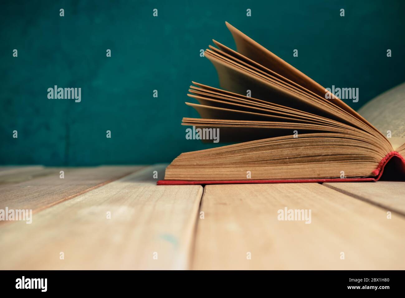 Beautiful ancient open old book on a red wooden table and dark-green ...