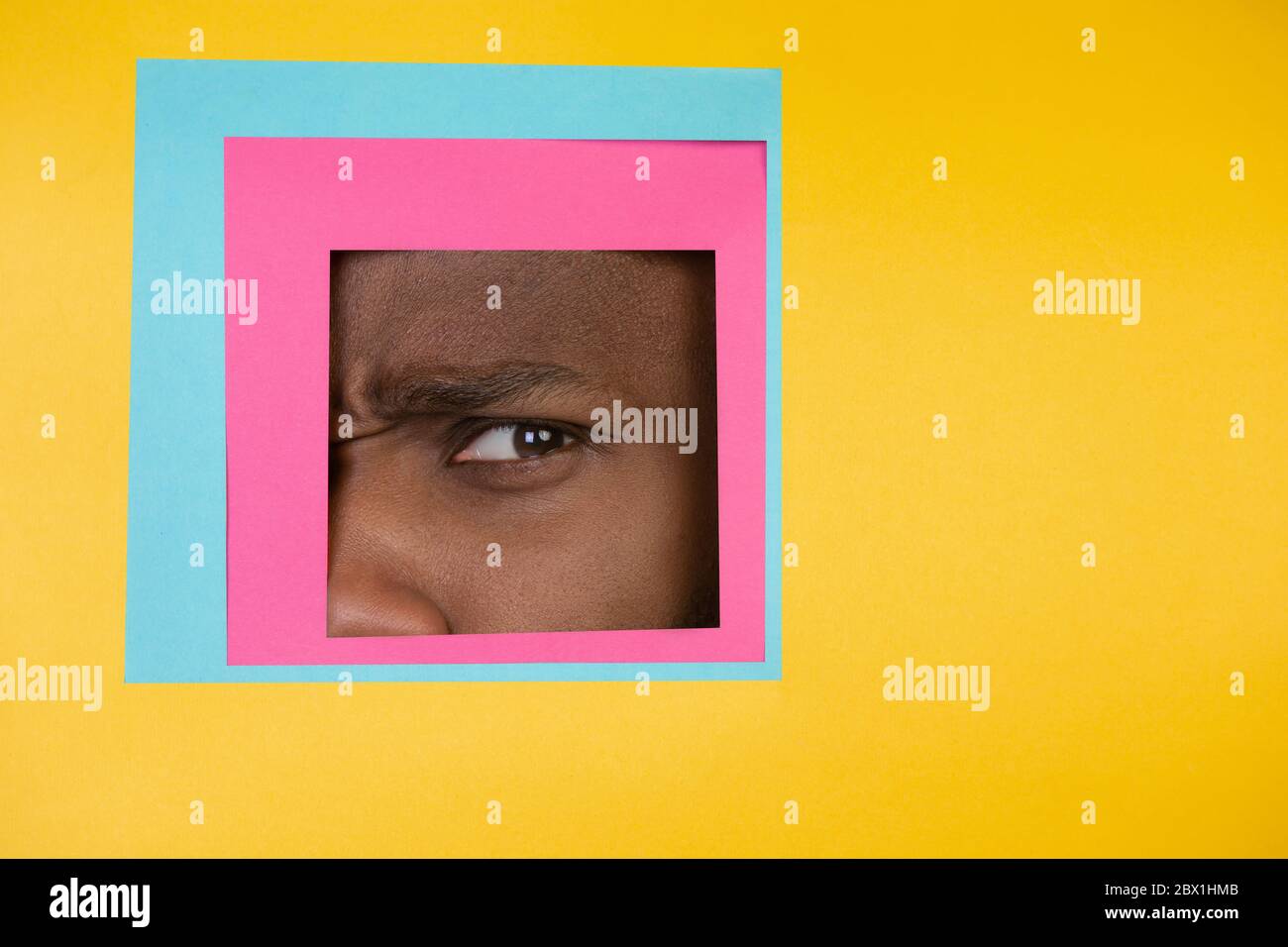 Scared. Eye of emotional african-american man peeks throught square in ...