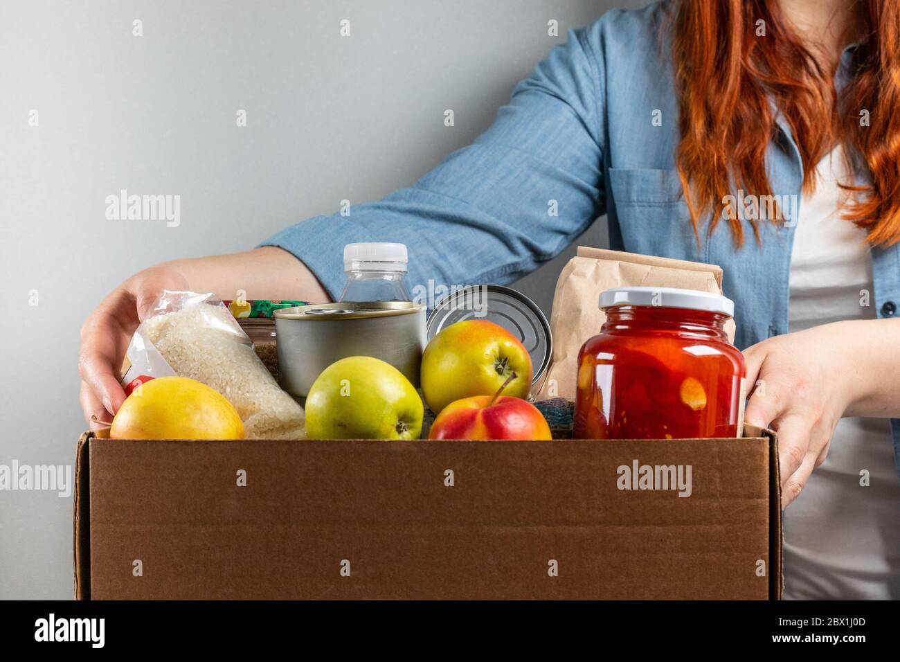 Woman hands hold food donation box with fruits, cereals, water and ...