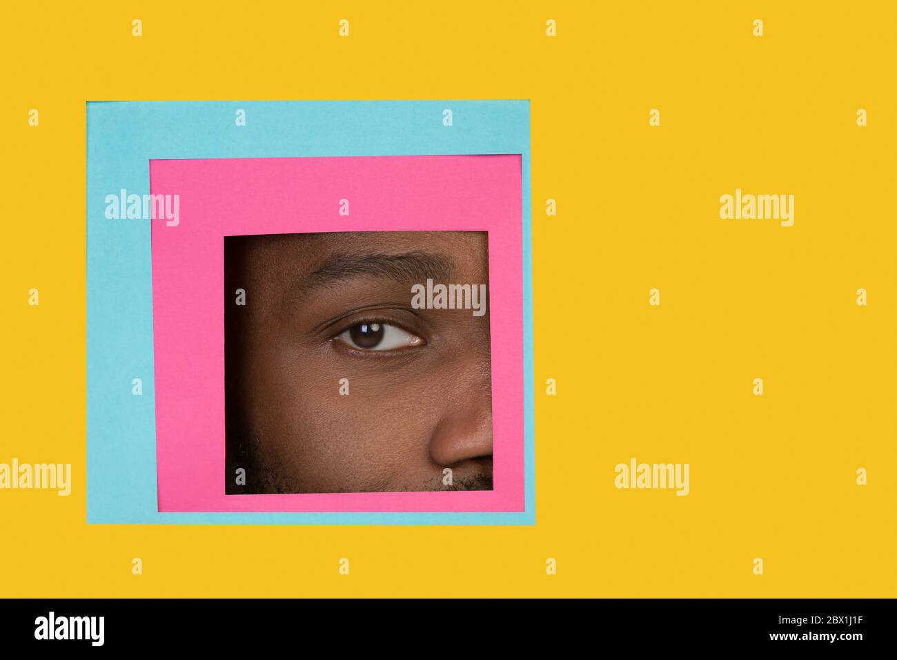 Calm. Eye of emotional african-american man peeks throught square in ...