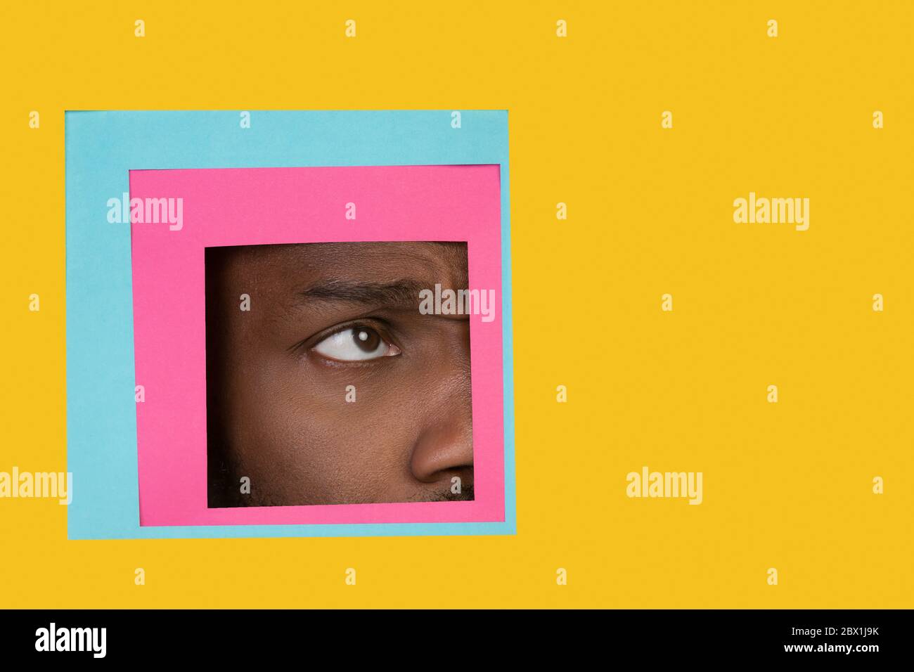 Doubt. Eye of emotional african-american man peeks throught square in ...