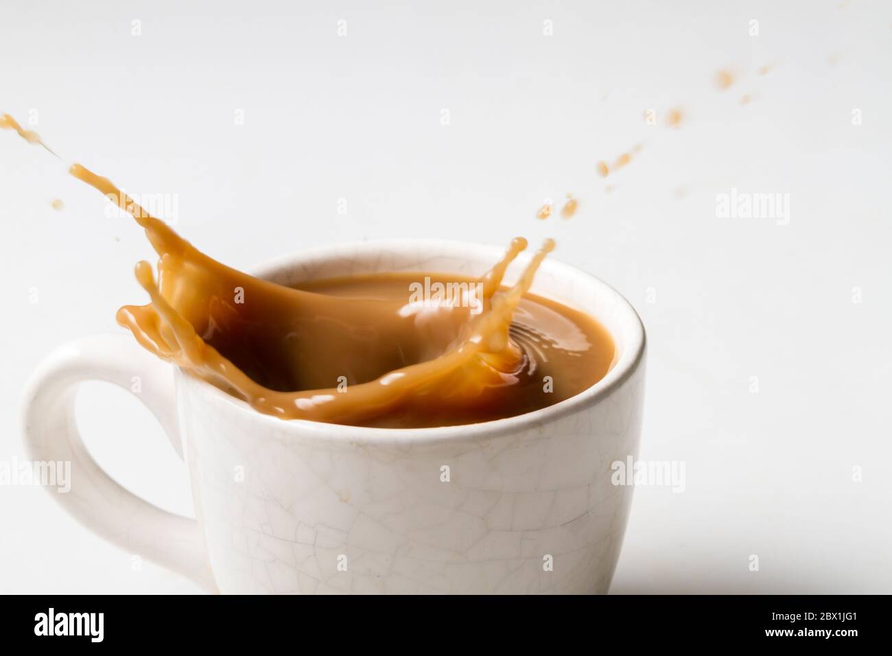Cup of splashing coffee on white background Stock Photo - Alamy