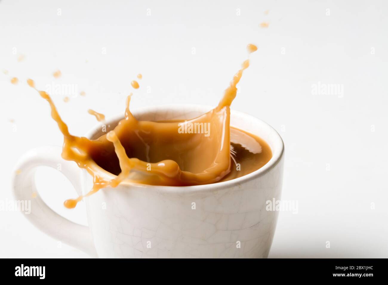 Cup of splashing coffee on white background Stock Photo - Alamy