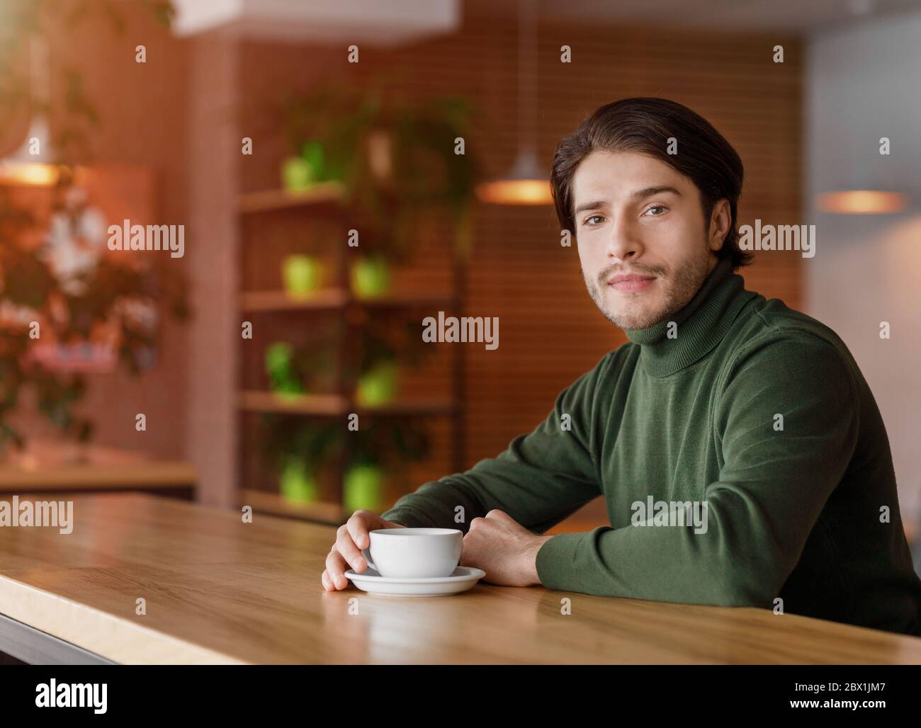 Young handsome man sitting alone at cafe, drinking coffee Stock Photo ...